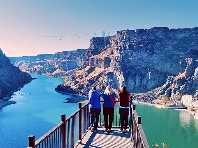 Three visitors sharing a moment of silent awe at the overlook. Sometimes the best conversations happen when nobody says a word.