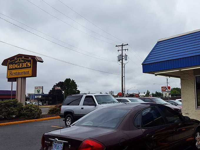 Roger's Restaurant sign stands sentinel in the parking lot, promising refuge from hunger in a sea of chain restaurants.
