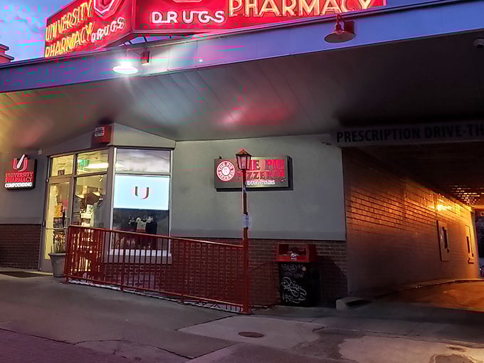 Tucked beneath a pharmacy, The Pie's red-lit entrance beckons pizza lovers into its cheese-laden lair.