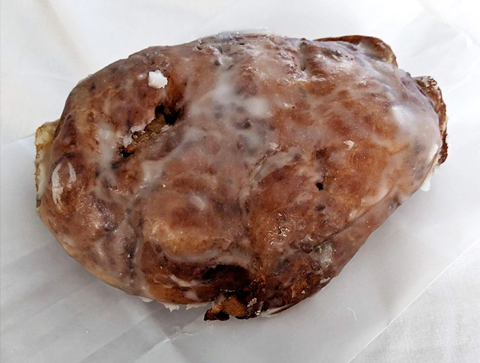 This apple fritter isn't just fried dough &ndash; it's a commitment. The glaze crackles with each bite, revealing cinnamon-spiced apple treasures within.