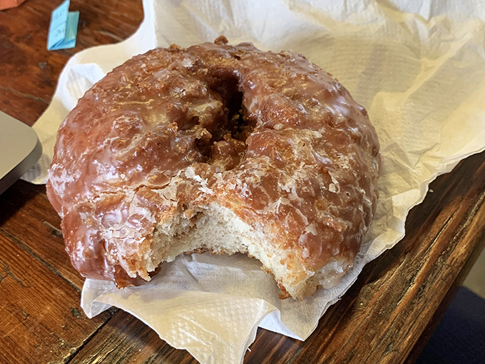 The apple fritter—that magnificent, craggly landscape of glazed peaks and valleys—sits like a monument to what fried dough can achieve.