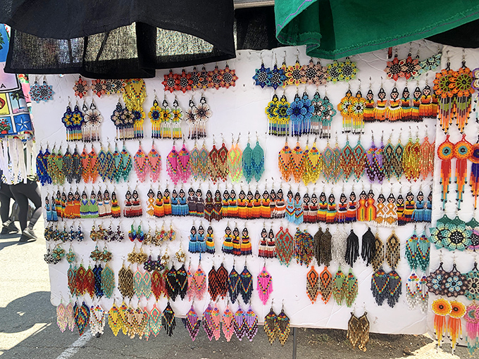 A kaleidoscope of handcrafted beaded earrings transforms a simple white display board into a mesmerizing wall of wearable art.