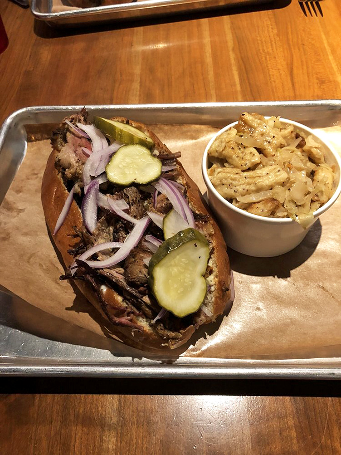 The beef sandwich arrives like a meaty masterpiece, those pickles and red onions cutting through the richness like a well-timed punchline after a heavy joke.