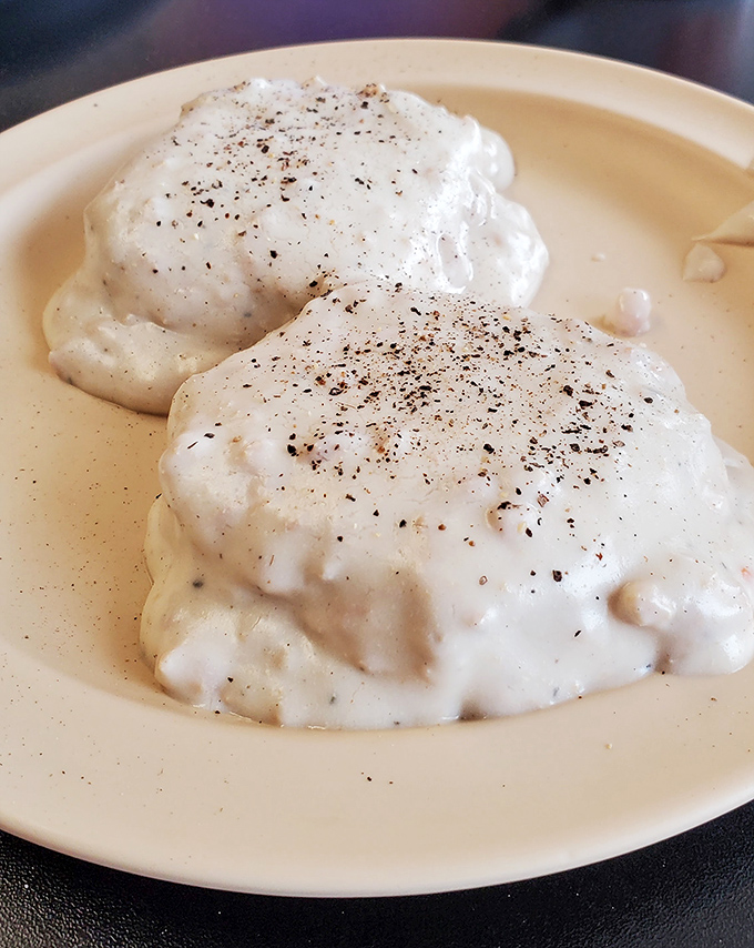 Biscuits and gravy that would make your Southern grandmother nod in approval. Creamy, peppery clouds of comfort on a simple beige plate.
