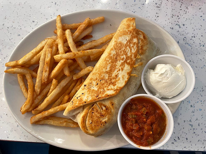 The breakfast burrito arrives like a tightly wrapped present, flanked by golden fries and the promise of a very good day ahead.