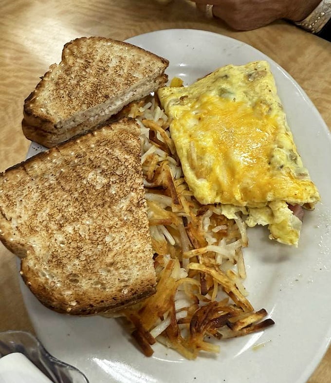 Breakfast of champions! That perfectly folded omelet nestled against crispy hash browns and toast is the morning trifecta we all deserve.