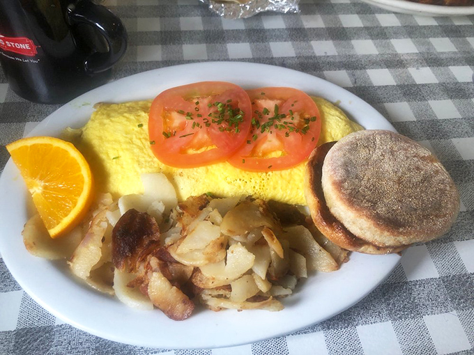 A proper breakfast plate that understands the sacred trinity: perfectly folded omelet, crispy hashbrowns, and an English muffin for structure.