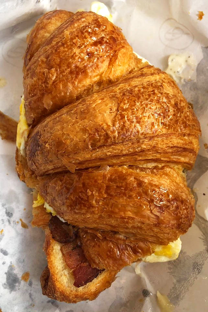 Not your average breakfast sandwich. This golden croissant cradles eggs and bacon in a buttery embrace that makes fast-food versions weep with inadequacy.