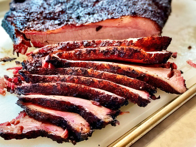 Brisket sliced thin enough to read through, with a smoke ring that tells tales of low-and-slow dedication. Carnivore poetry on a plate.