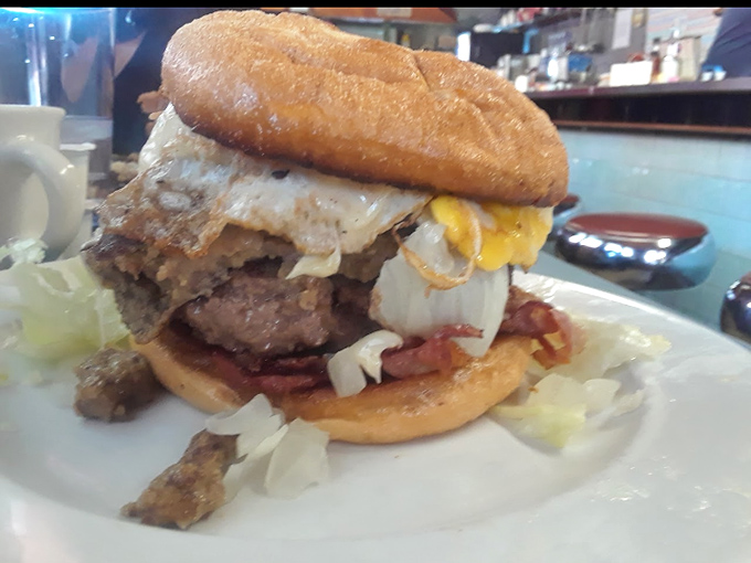 This isn't just a burger &ndash; it's a gravity-defying monument to morning excess. The egg yolk waiting to cascade is nature's perfect sauce.