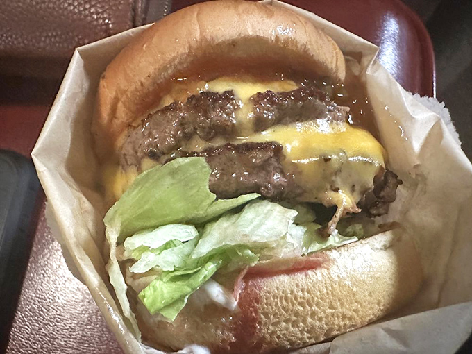 Behold the star of the show: a perfectly proportioned cheeseburger wrapped in paper, where every ingredient knows its role and plays it brilliantly.