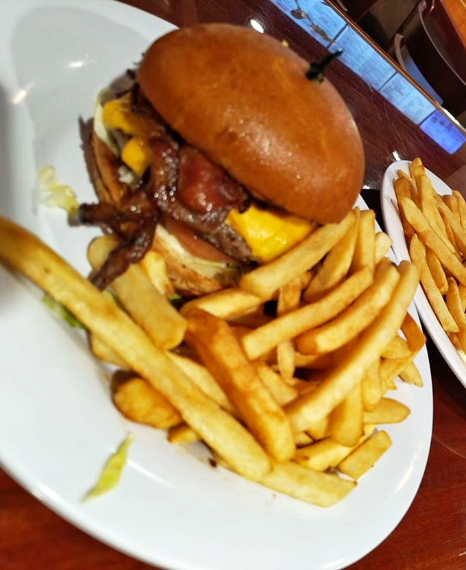 This isn't just a burger; it's a towering monument to beef with melty cheese cascading down its sides like a yellow waterfall.