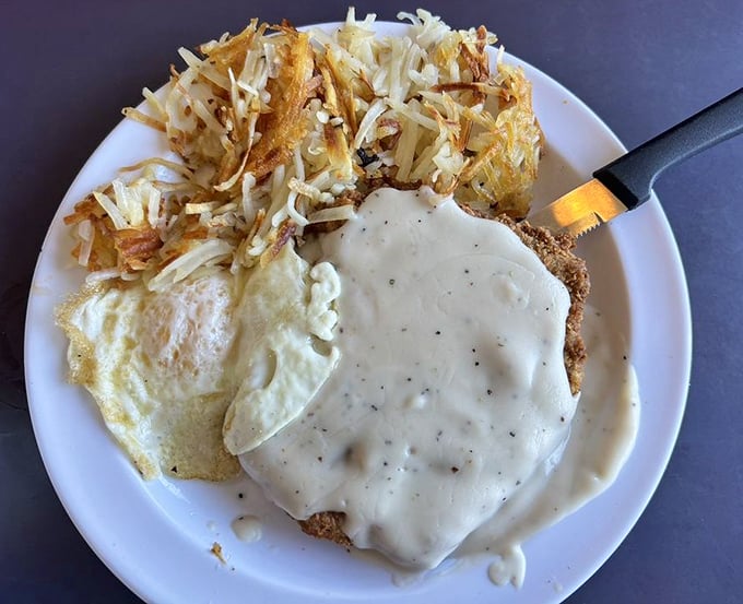 Comfort food royalty: crispy chicken fried steak smothered in country gravy alongside golden hash browns that crunch in all the right places.