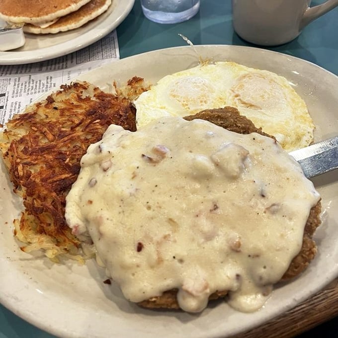 Chicken fried steak smothered in country gravy alongside crispy hashbrowns and eggs—the breakfast equivalent of a warm hug from your favorite grandma.
