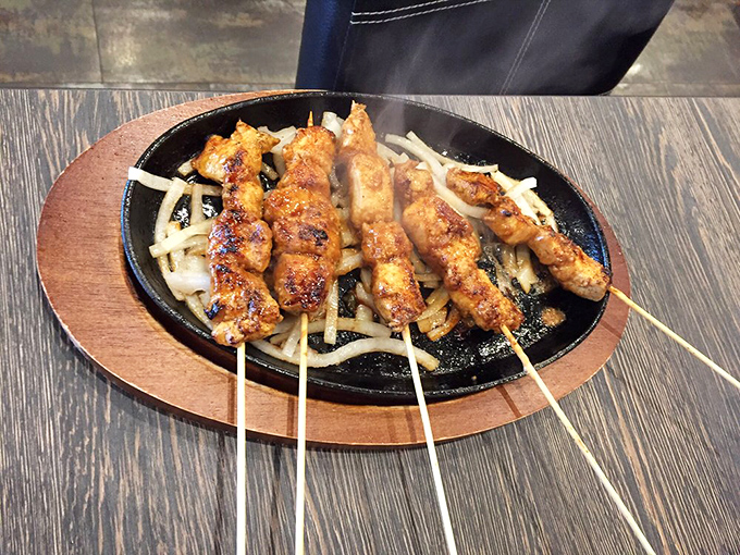 Chicken skewers that could make a vegetarian weep with temptation, perfectly charred and resting on a bed of saut&eacute;ed onions.