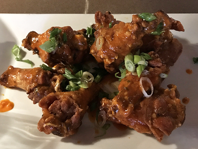 These wings arrive glistening like edible jewels, garnished with scallions that actually serve a purpose beyond looking pretty.