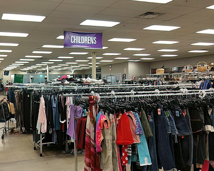 The children's section: where parents discover the true meaning of "they'll outgrow it before they wear it out." Purple signs guide you to kid-sized fashion miracles.