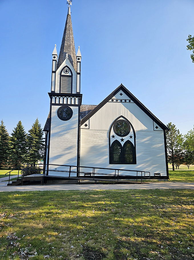 The historic white church stands like a pristine wedding cake against the blue sky, its steeple reaching toward heaven with architectural ambition.