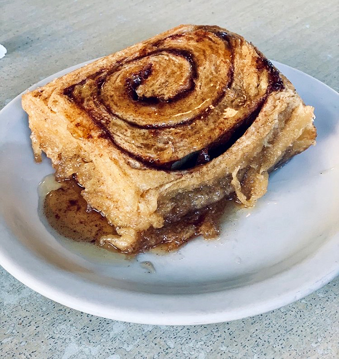 The cinnamon roll arrives looking like it just won a beauty pageant. Spiral perfection with that glistening glaze that makes you want to frame it before devouring it.