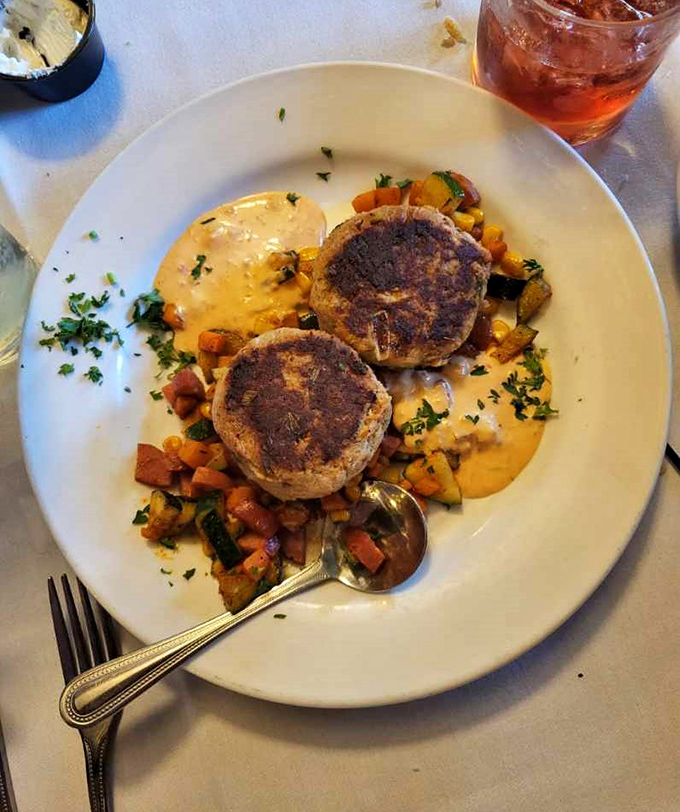 Perfectly golden crab cakes nestled on a bed of colorful vegetables&mdash;proof that inland Indiana knows its way around seafood when in the right hands.