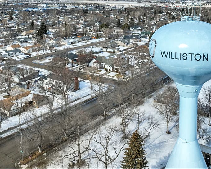 The iconic Williston water tower stands sentinel over neighborhoods where affordable homes and tree-lined streets create the quintessential American dream landscape.