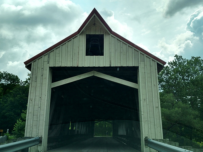 The bridge's entrance stands like a portal to simpler times, its wooden frame creating a perfect rectangle that frames the journey ahead.
