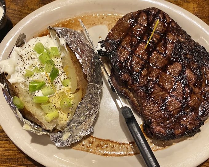 The filet mignon shares its plate with a loaded baked potato – a partnership more harmonious than most marriages.