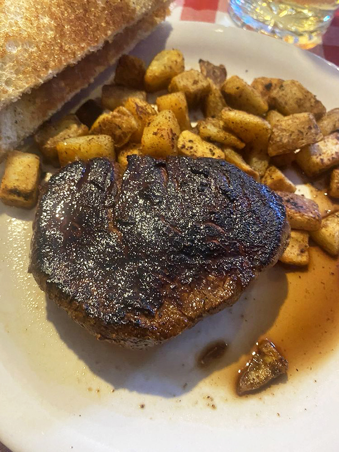 The filet mignon sits in a pool of its own juices like royalty on a throne, surrounded by perfectly seasoned potatoes.