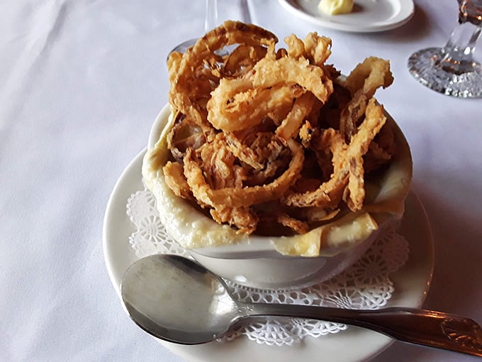 French onion soup crowned with crispy onion straws so tall, they're practically reaching for the historic ceiling beams.
