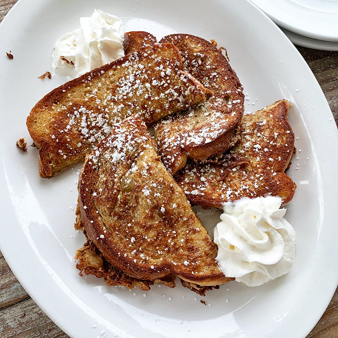 The French toast at Doreen's doesn't just arrive at your table—it makes an entrance, dressed in powdered sugar with whipped cream accessories.