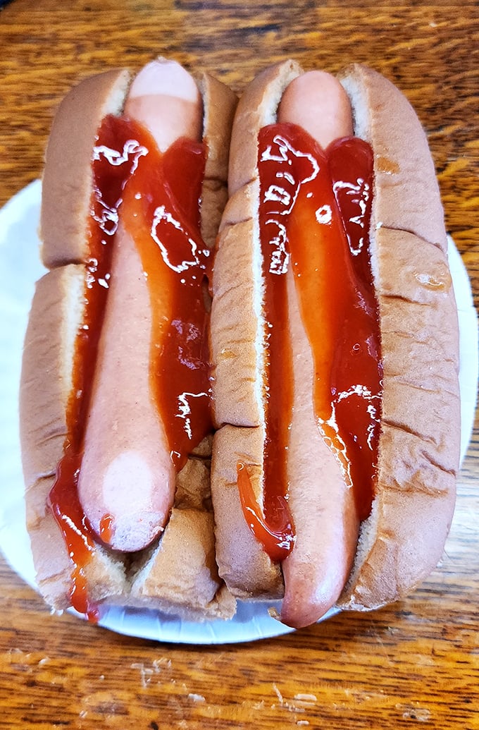 Hot dogs so perfectly simple they make you question why anyone would complicate such a beautiful thing. The ketchup artistry alone deserves applause.