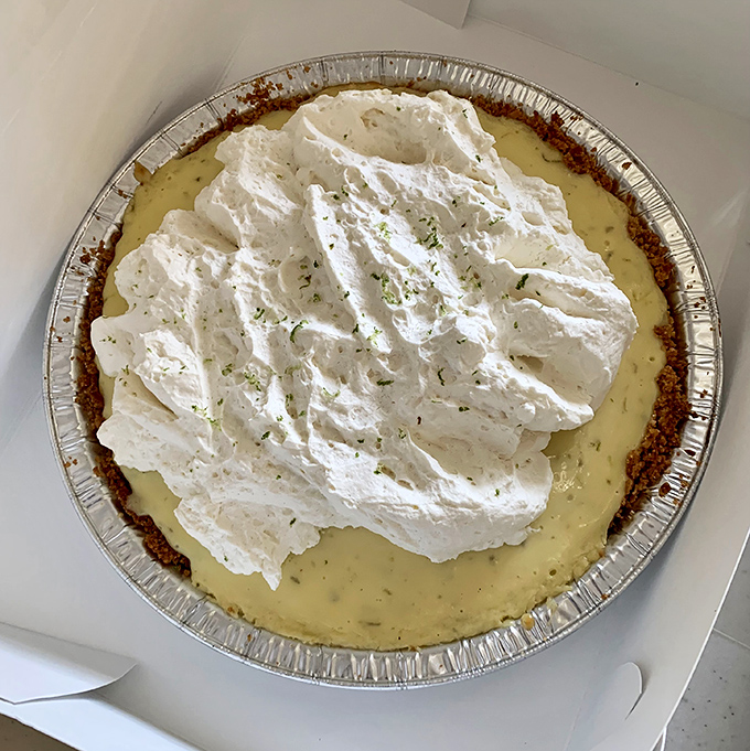 Key Lime pie topped with clouds of whipped cream and lime zest. The graham cracker crust isn't just holding filling—it's supporting dreams.