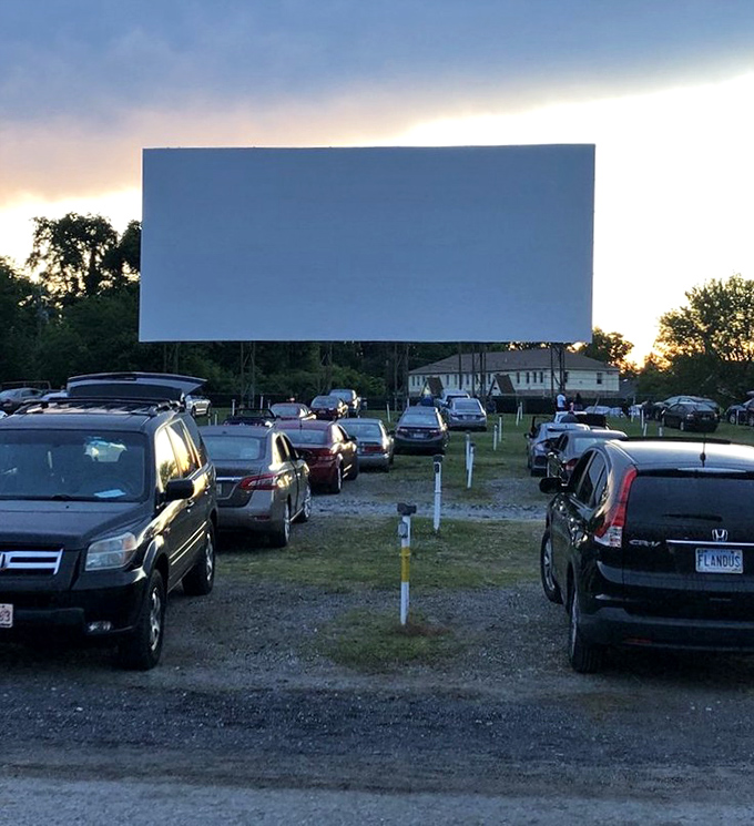 Between rows of cars, the massive screen commands attention as day surrenders to dusk.