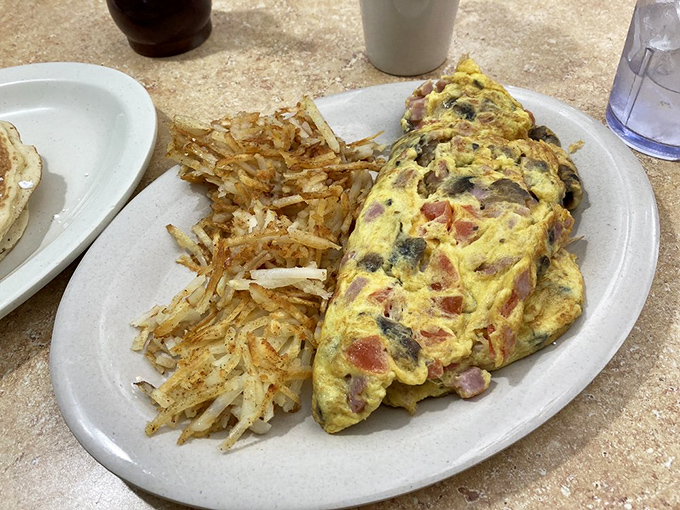 This isn't just an omelet; it's a masterpiece of morning engineering &ndash; packed with fillings and paired with hash browns crisped to golden perfection.