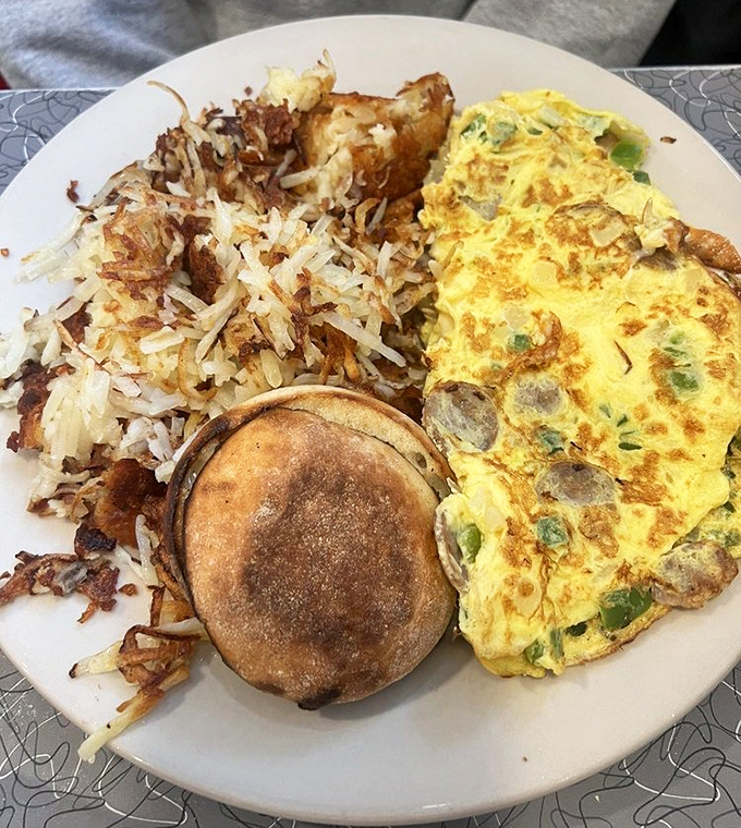 Breakfast harmony achieved: a fluffy omelet, crispy hash browns, and an English muffin. The holy trinity of morning satisfaction. 