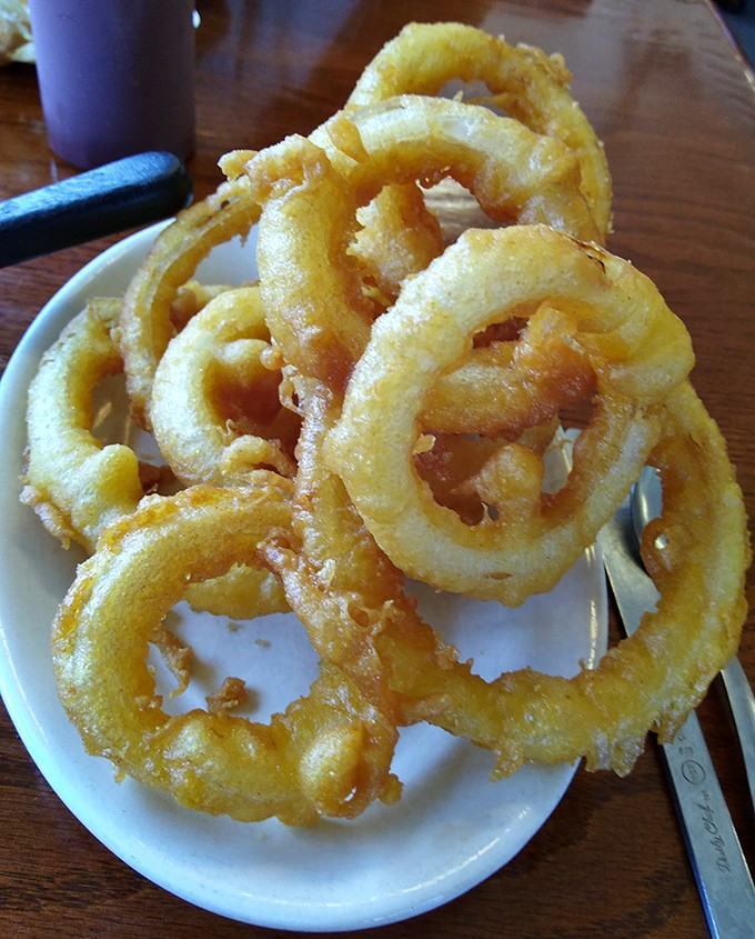Onion rings that shatter with each bite, golden-brown halos of crispy perfection that make you wonder why anyone bothers with french fries.