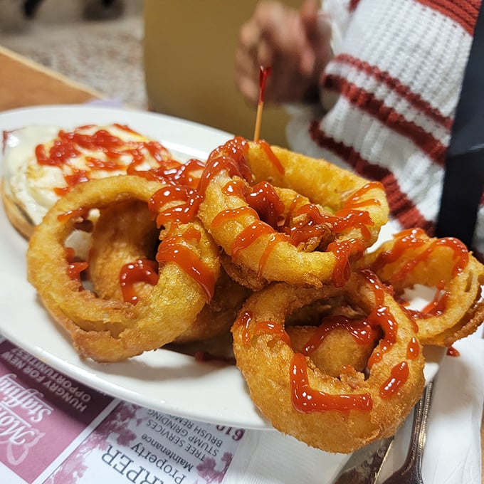 Golden onion rings drizzled with ketchup &ndash; a perfect crispy side to complement Llanerch's hearty main dishes. Classic diner indulgence at its finest.