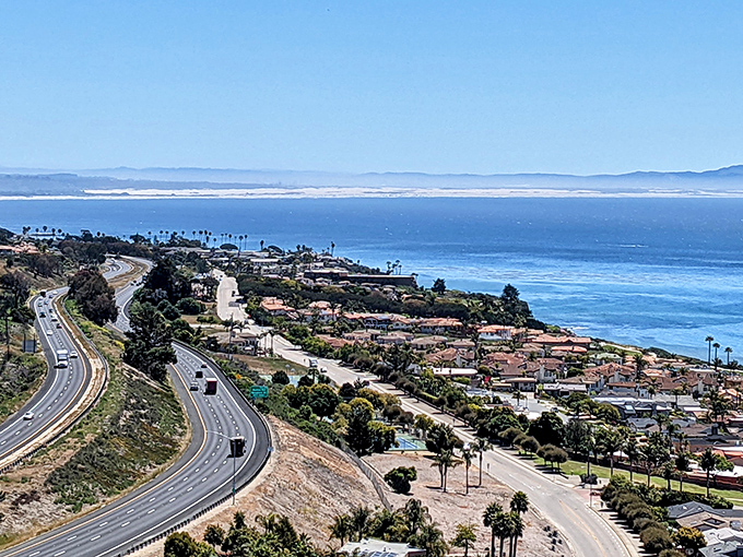 Highway hugs coastline as Avila Beach unfolds below like nature's perfect postcard. The view that makes you forget every traffic jam you endured to get here.