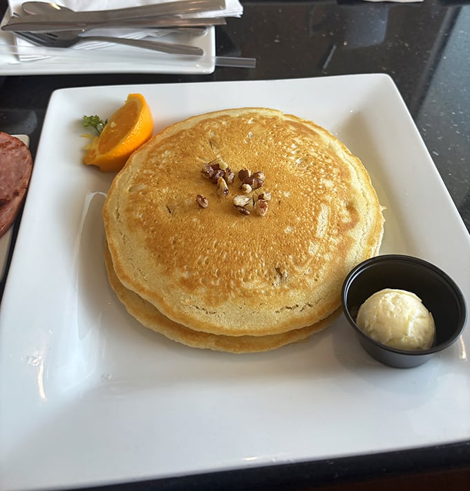 These aren't just pancakes; they're fluffy golden discs of joy topped with nuts and served with a side of "why don't mine ever look like this at home?"