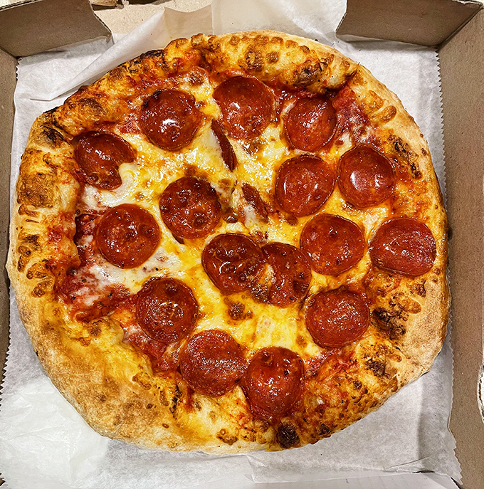 Pepperoni pizza perfection in its natural habitat &ndash; a golden-brown crust supporting the perfect ratio of sauce, cheese, and those gloriously curled pepperoni cups.