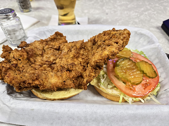 The pork tenderloin sandwich—an Indiana classic that refuses to be contained by mere bread. It's the Dolly Parton of sandwiches: big, beloved, and unforgettable.