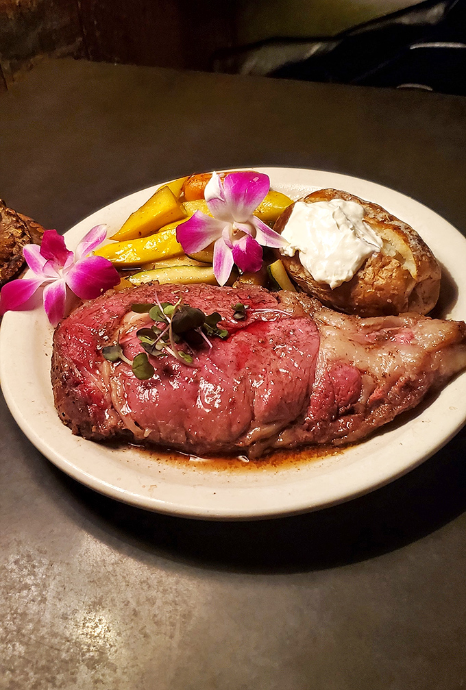 Prime rib so tender it practically surrenders to your fork, accompanied by a loaded baked potato that's having its own moment of glory.