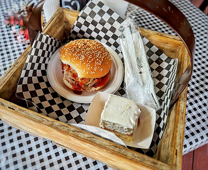 The sesame-topped bun barely contains its treasures. This pulled pork sandwich sits regally in its wooden basket throne, accompanied by a slice of heaven.
