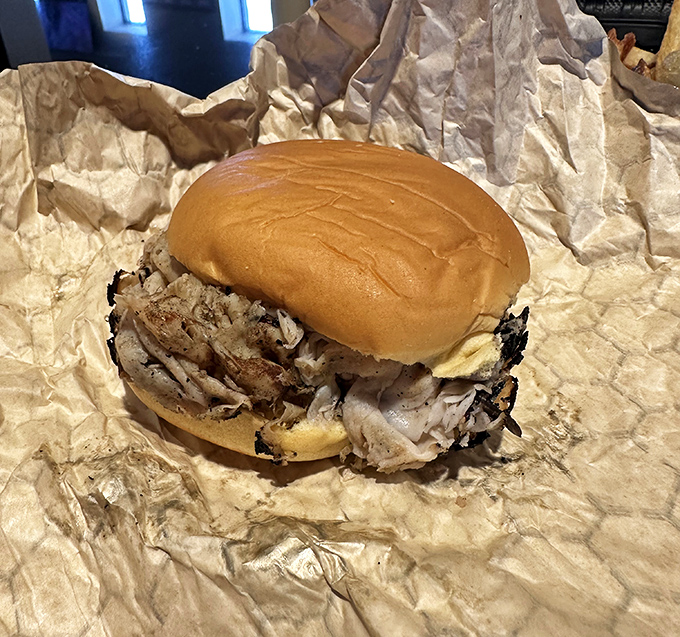 This pulled pork sandwich doesn't need fancy garnishes &ndash; just a kaiser roll struggling heroically under the weight of perfectly smoked meat. Poetry in sandwich form.