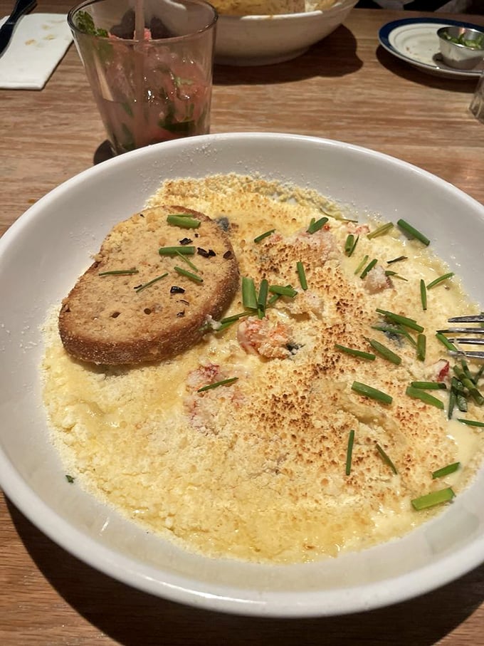 Seafood decadence in a bowl &ndash; creamy sauce, toasted bread, and what appears to be seafood ravioli. The sprinkle of chives adds color to this indulgent comfort dish.