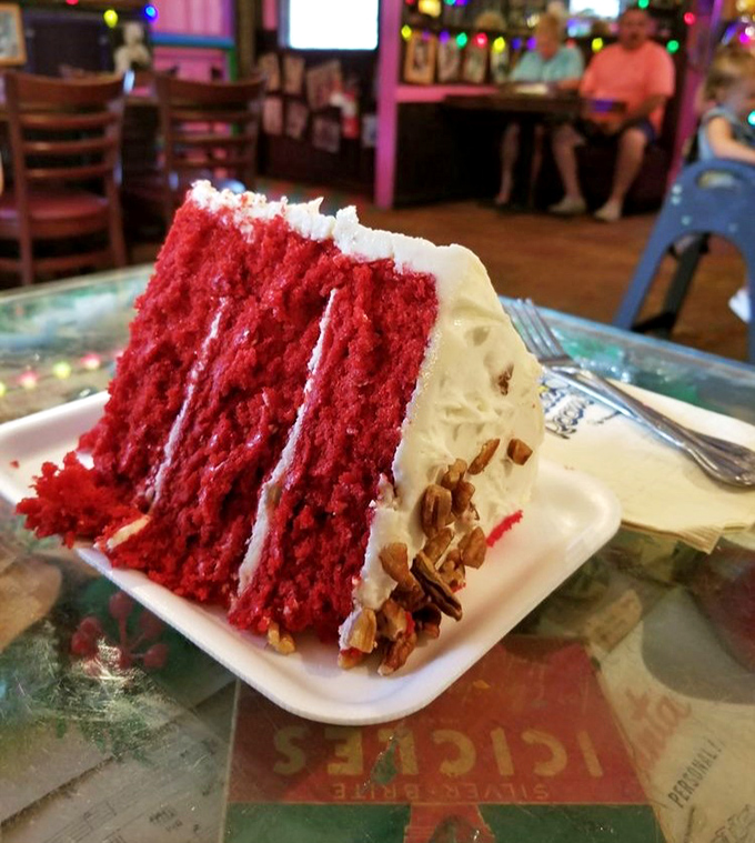 The Red Velvet Cake stands tall enough to require FAA clearance, with layers that make geologists jealous and frosting that dreams are made of.