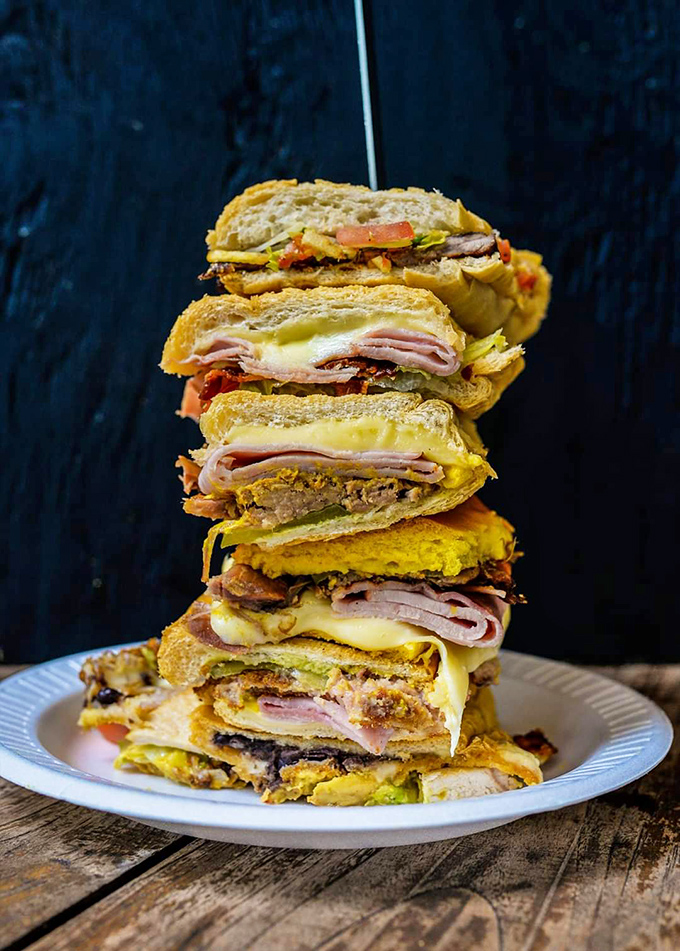 Behold the architectural marvel that is the Cuban sandwich tower – layers of ham, roasted pork, and cheese creating a skyscraper of flavor.