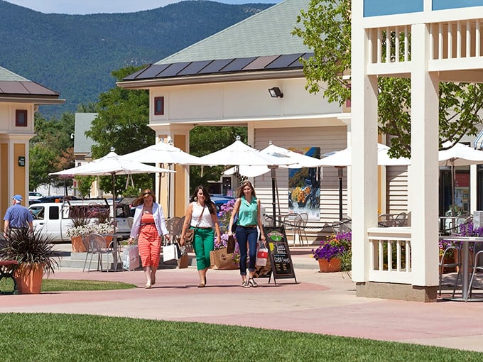 The ultimate New Hampshire power walk: three friends, shopping bags in hand, against a backdrop of mountains that make every purchase more scenic.