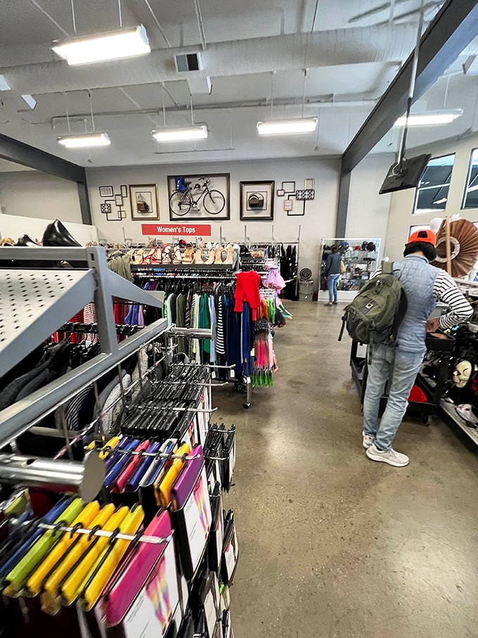 Women's tops cascade in rainbow formation, each hanger holding someone's "I'll wear this someday" promise.