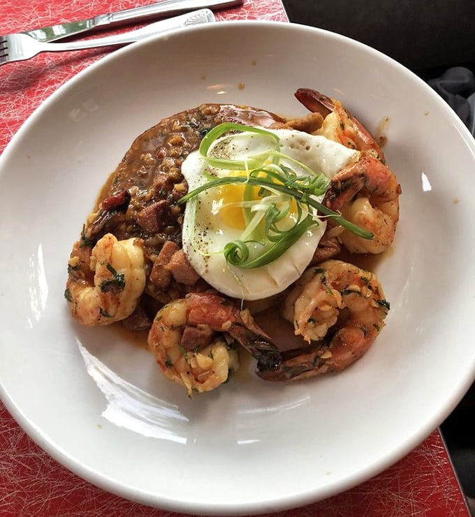 Shrimp and grits elevated to an art form – plump crustaceans surrounding a perfectly poached egg that's just waiting to release its golden treasure.